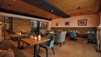 Interior de restaurante moderno com teto de madeira, mesas, cadeiras e área de estar.