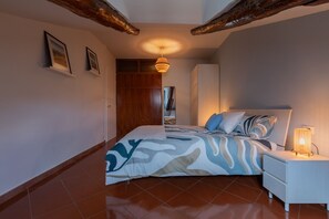 Quarto com cama, mesa de cabeceira e luminária pendente.