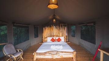 Quarto tipo tenda com cama, móveis de madeira e luminária pendente.