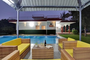 Uma área de piscina com mobiliário de vime e um espaço coberto para sentar.