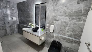 Um banheiro moderno com painel de mármore, pia preta, espelho grande e vaso sanitário.