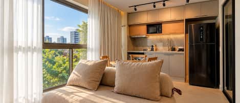 Quarto moderno com uma janela grande, um sofá com almofadas e vista para a cidade.
