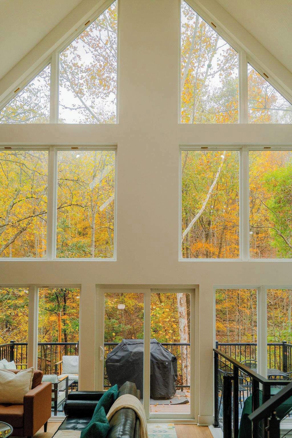 Um quarto amplo com grandes janelas que oferecem vista para a folhagem outonal.