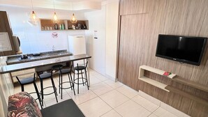 Uma cozinha moderna com área de refeições, sofá e televisão na parede.