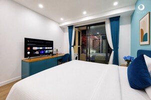 Quarto de hotel moderno com uma cama, uma escrivaninha com TV de tela plana, uma janela com cortinas e uma obra de arte pendurada na parede.