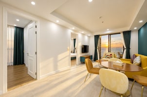 Sala moderna com área de jantar, televisão e varanda com vista para o pôr do sol.