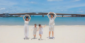 Uma família numa praia, com uma ponte ao fundo.