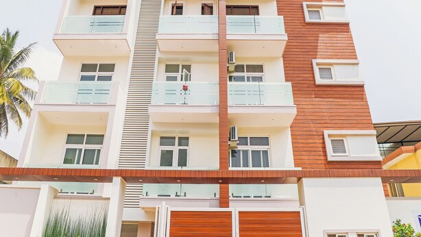 Um edifício residencial com vários andares, varandas, uma escadaria central e uma fachada com detalhes em branco e madeira.