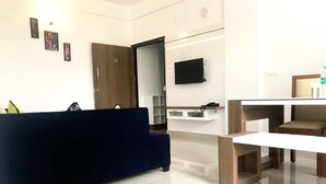 Uma sala de estar moderna com um sofá azul escuro, uma mesa de centro branca e um armário de madeira.