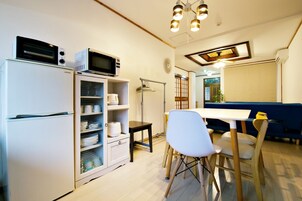 Uma cozinha compacta com geladeira, micro-ondas e um pequeno espaço de refeições com mesa e cadeiras.