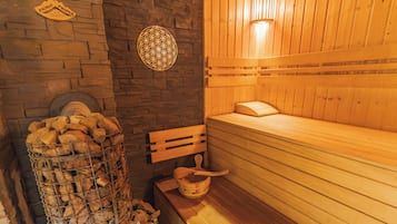 Uma sauna com bancos de madeira, parede de pedra e um recipiente de metal com pedras.