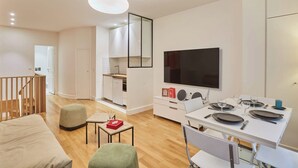 Um apartamento moderno com área de jantar, kitchenette e TV fixada na parede.