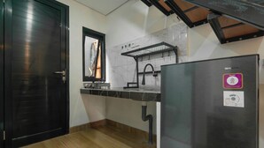 Uma cozinha moderna com geladeira de aço inoxidável, porta preta, painel de azulejos e janela sobre a pia.