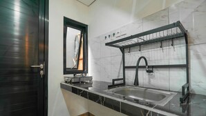 Cozinha moderna com bancada preta, pia, janela e porta.