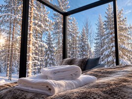 Quarto acolhedor com uma grande janela com vista para uma floresta coberta de neve.