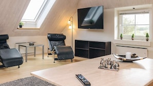 Uma sala de estar moderna em estilo loft, com pé direito alto, claraboias, televisão de tela plana, lareira e espaço de jantar.