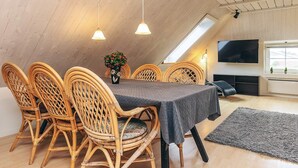 Uma sala de jantar com mesa, cadeiras e televisão.