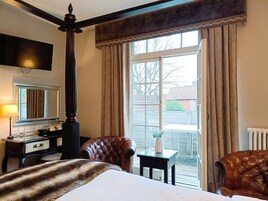 Quarto com uma cama grande, cômoda, espelho, janela com cortinas e vista para o exterior.