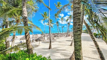 Perto da praia, areia branca, espreguiçadeiras, guarda-sóis