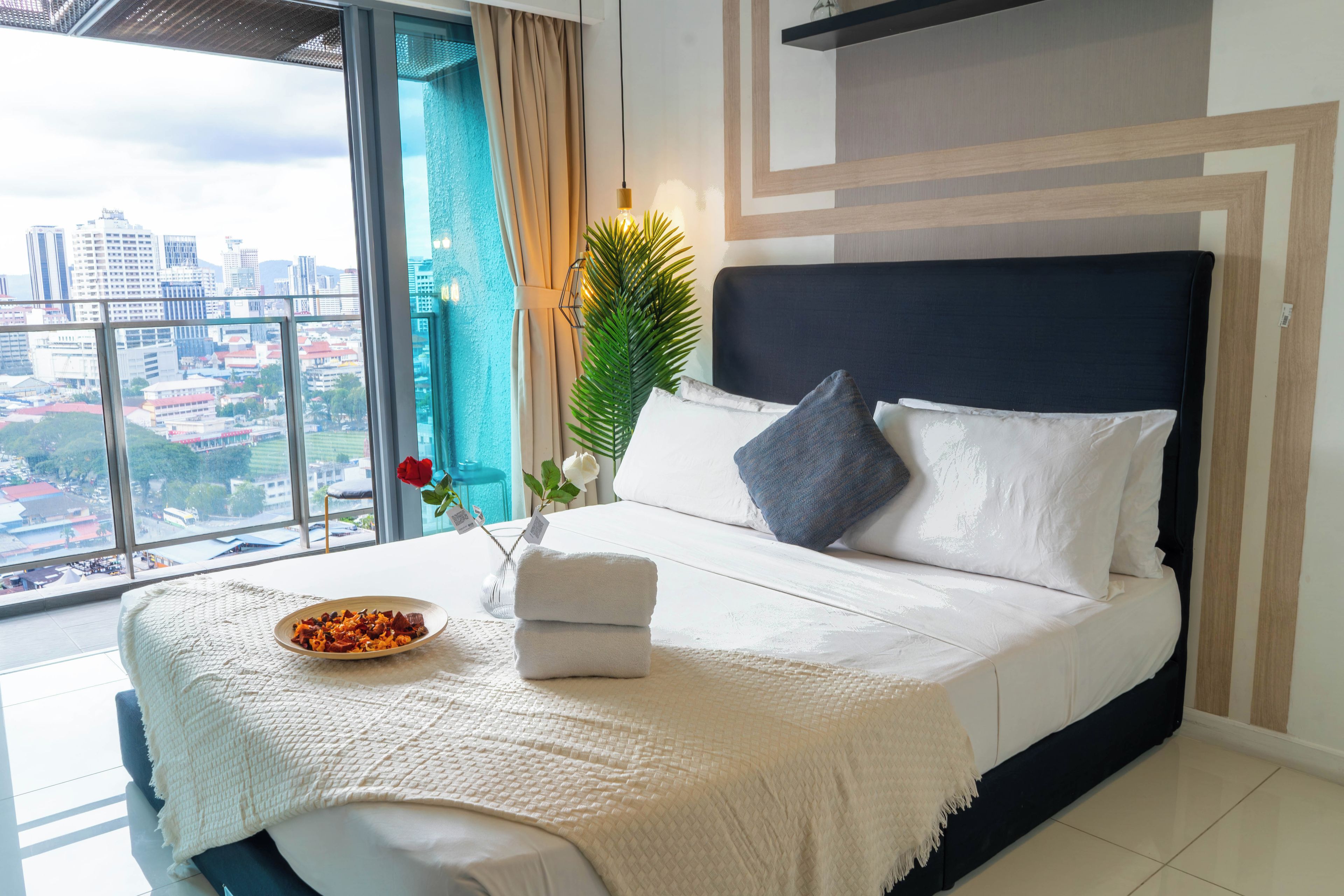 Quarto de hotel com uma cama grande, vista para a cidade e uma varanda.