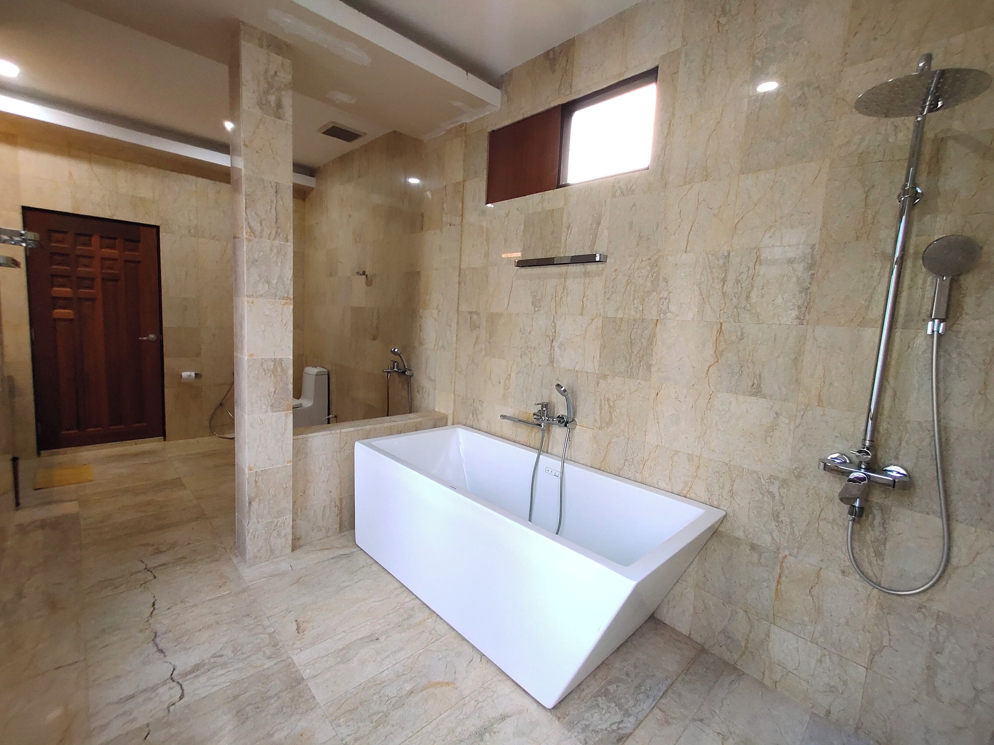 Um banheiro moderno com uma banheira grande, chuveiro e piso de mármore.