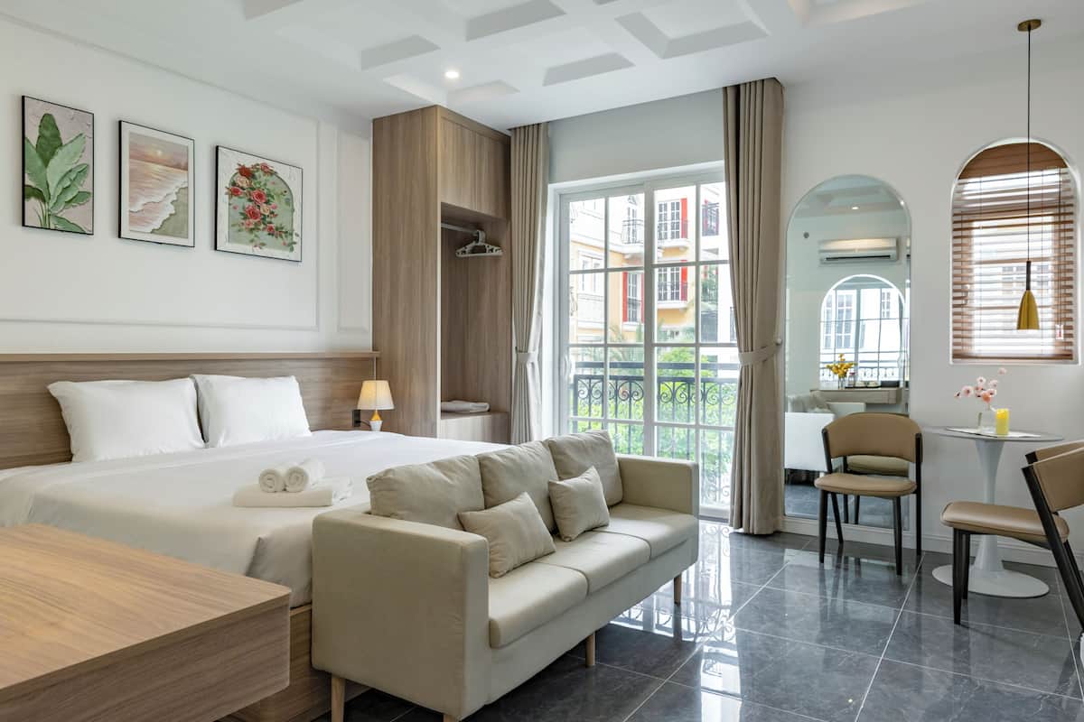 Quarto de hotel com cama, sofá, escrivaninha e vista para o exterior.