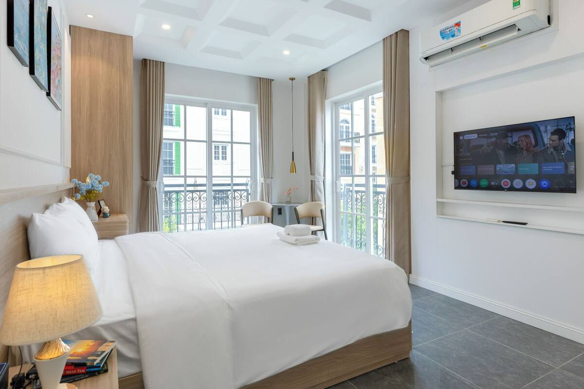Quarto de hotel com cama, televisão, escrivaninha e varanda com vista.