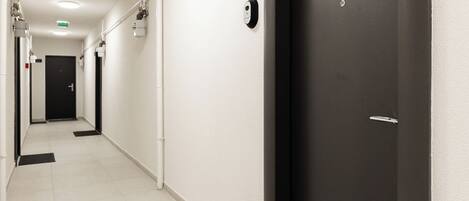 Um corredor com uma porta preta, um tapete de entrada e uma placa sobre a porta.