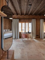 Um quarto com teto de madeira, uma cama, uma escrivaninha e uma cadeira.