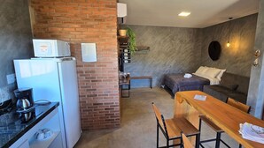 Um espaço compacto com cozinha compacta, área de refeições e sala de estar com sofá e mesa.