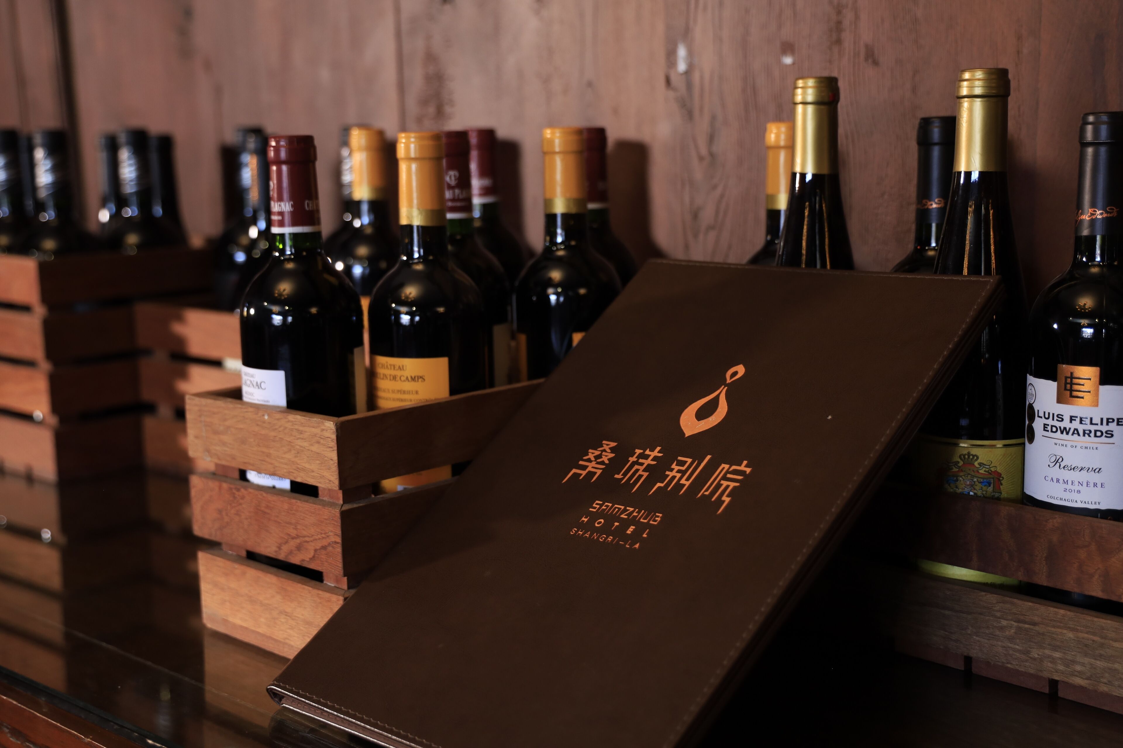 Uma caixa de madeira cheia de garrafas de vinho e uma caixa marrom com caracteres chineses.