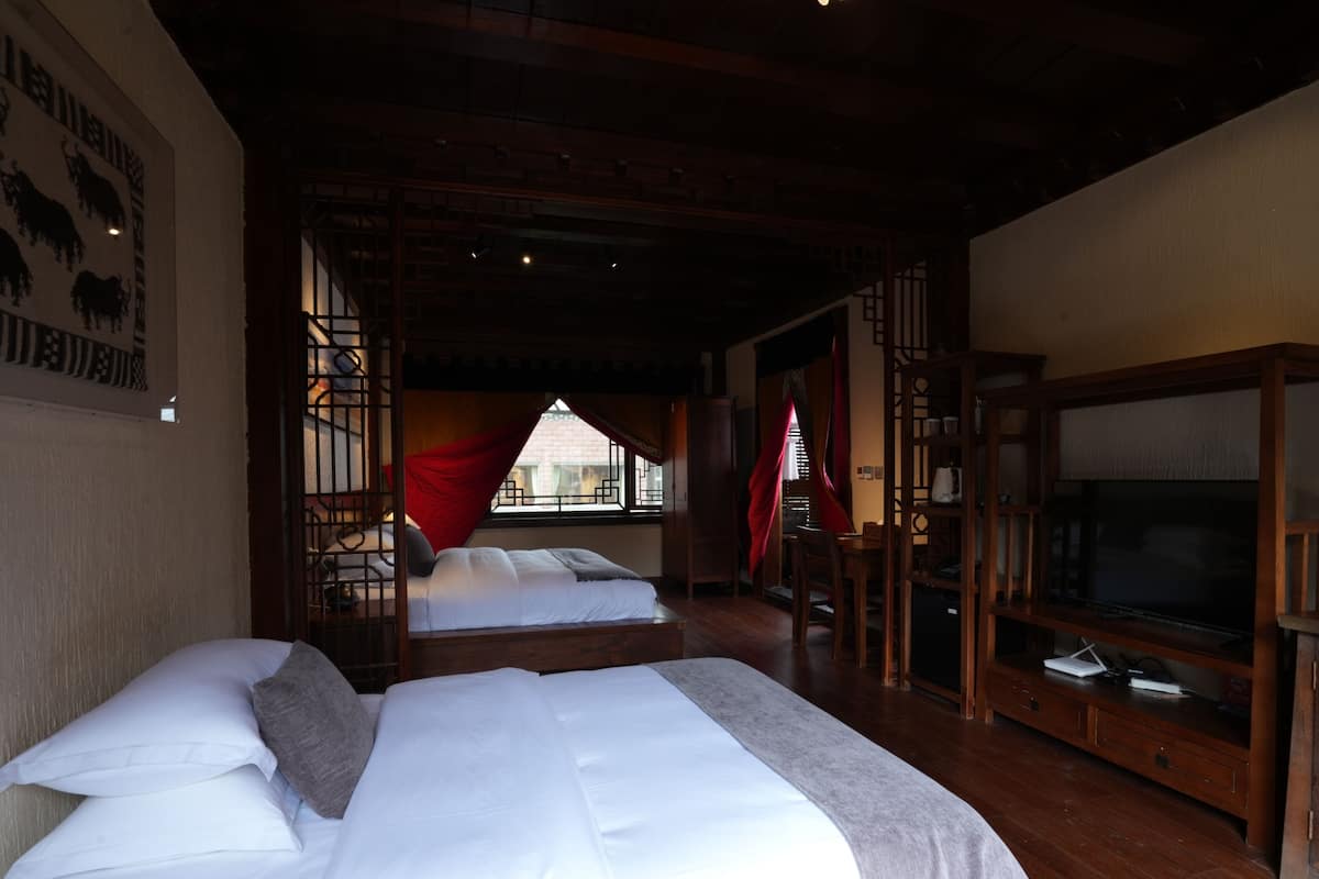 Quarto de hotel com duas camas, televisão e um armário de madeira.