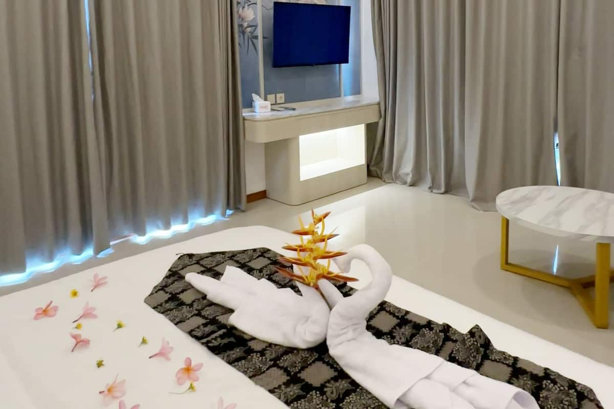 Quarto de hotel com cama, televisão na parede e secretária com cadeira.