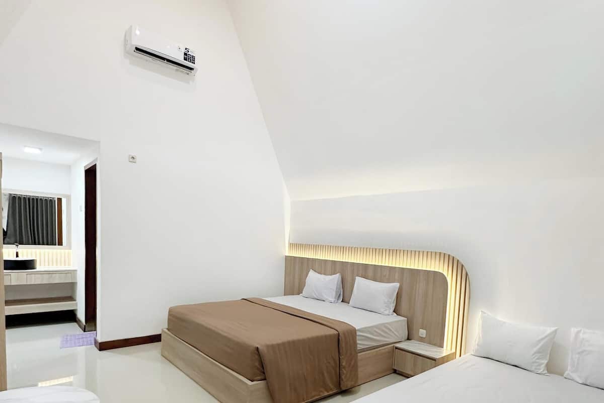 Quarto de hotel moderno com uma cama grande, uma cama menor e uma escrivaninha com cadeira.