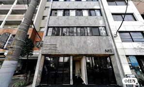 Um edifício de vários andares com fachada moderna, apresentando uma placa 'MS' em destaque no andar térreo.