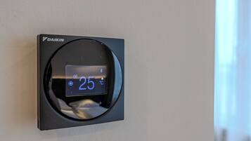 Um termostato com a marca 'DAIKIN' e a temperatura indicada em 25°C.