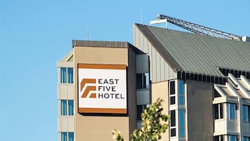 Edifício de hotel com uma placa indicando 'EAST FIVE HOTEL' e uma grua no telhado.