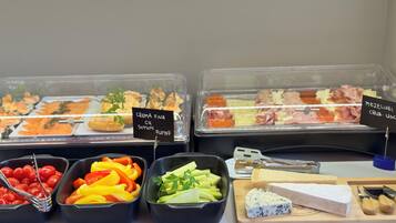 Buffet com diversos alimentos, incluindo queijo, frutas e legumes.