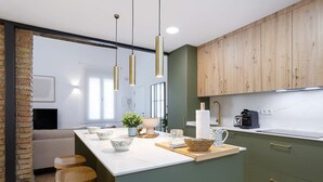Cozinha moderna com ilha central, armários de madeira e iluminação pendente.