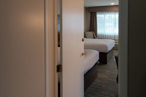Quarto de hotel com duas camas, piso coberto por carpete e janela com cortinas.