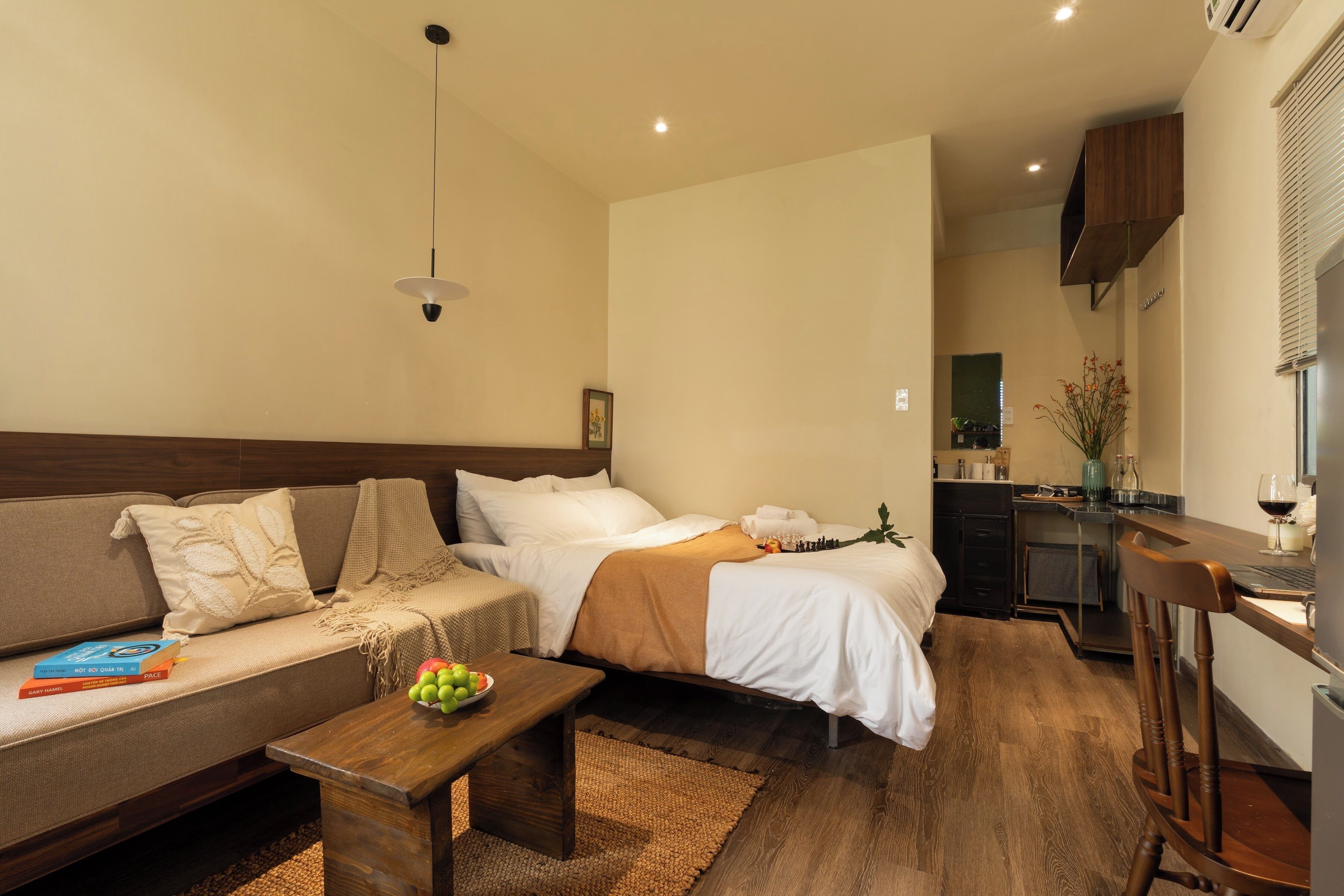 Quarto de hotel moderno com sofá, cama, mesa de jantar e cozinha.