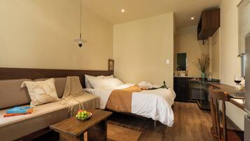 Quarto de hotel moderno com sofá, cama, mesa de jantar e cozinha.