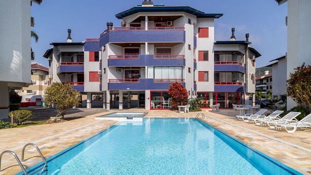Um hotel com piscina, várias varandas e fachada revestida com azulejos vermelhos e azuis.