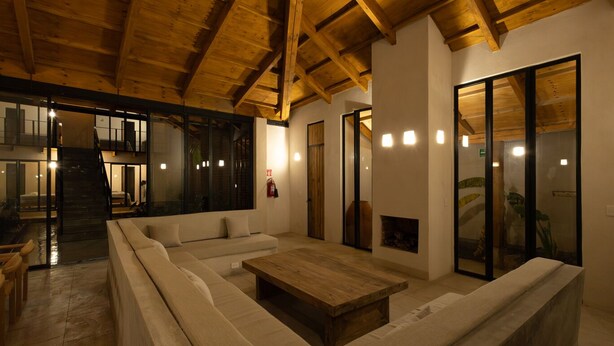 Um interior moderno com teto de madeira, um sofá grande e uma lareira.
