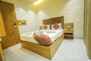 Quarto de hotel com cama de madeira, mesa de cabeceira e guarda-roupa.