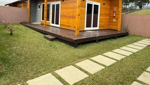Uma cabana de madeira com telhado inclinado, janelas amplas e um pequeno alpendre.