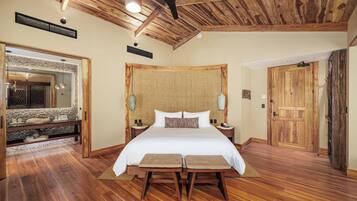 Um quarto espaçoso com uma cama grande, cabeceira de madeira, mesas de cabeceira e piso de madeira.