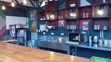 Uma cozinha com bancada de madeira, eletrodomésticos de aço inoxidável e prateleiras de madeira com diversos utensílios de cozinha.