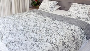 Quarto de hotel moderno com uma cama grande, cabeceira de mármore e vista para a cidade.
