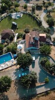 Vista aérea de uma área residencial com piscina, uma casa pequena e um carro estacionado perto.
